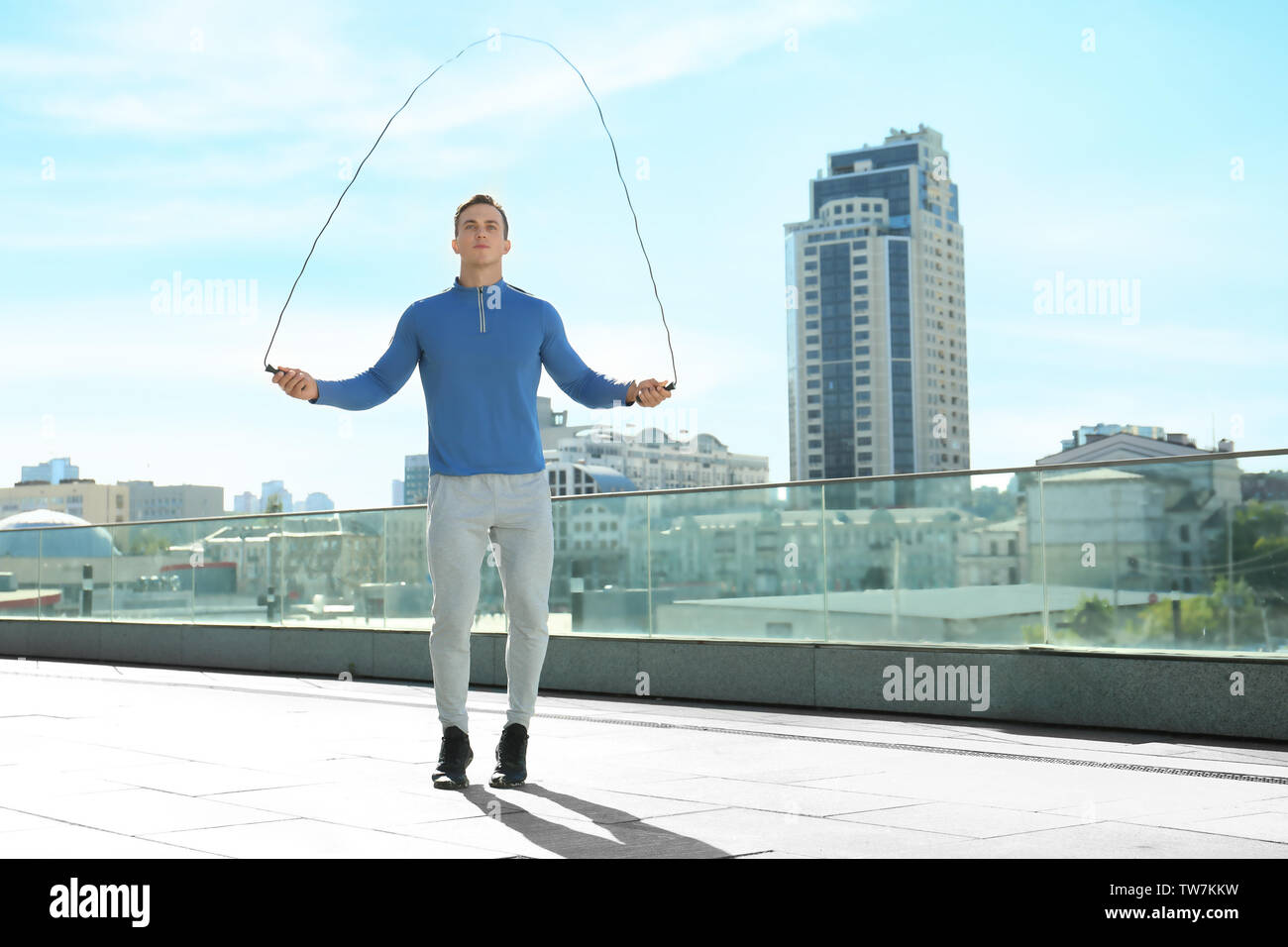 Sporty young man jumping rope outdoors Stock Photo - Alamy