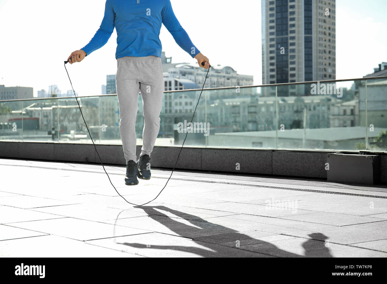 Sporty young man jumping rope outdoors Stock Photo - Alamy