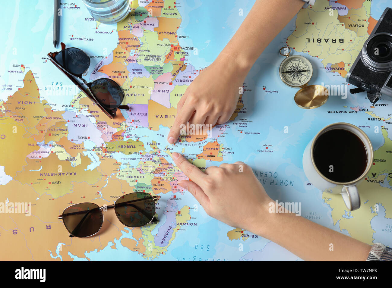 Female tourists pointing at world map on table Stock Photo - Alamy