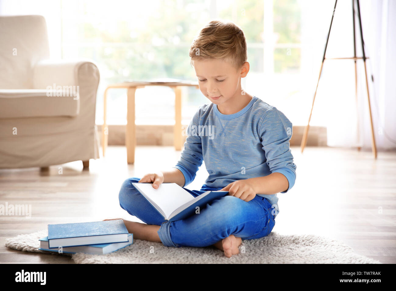 Cute little boy reading on floor at home Stock Photo - Alamy