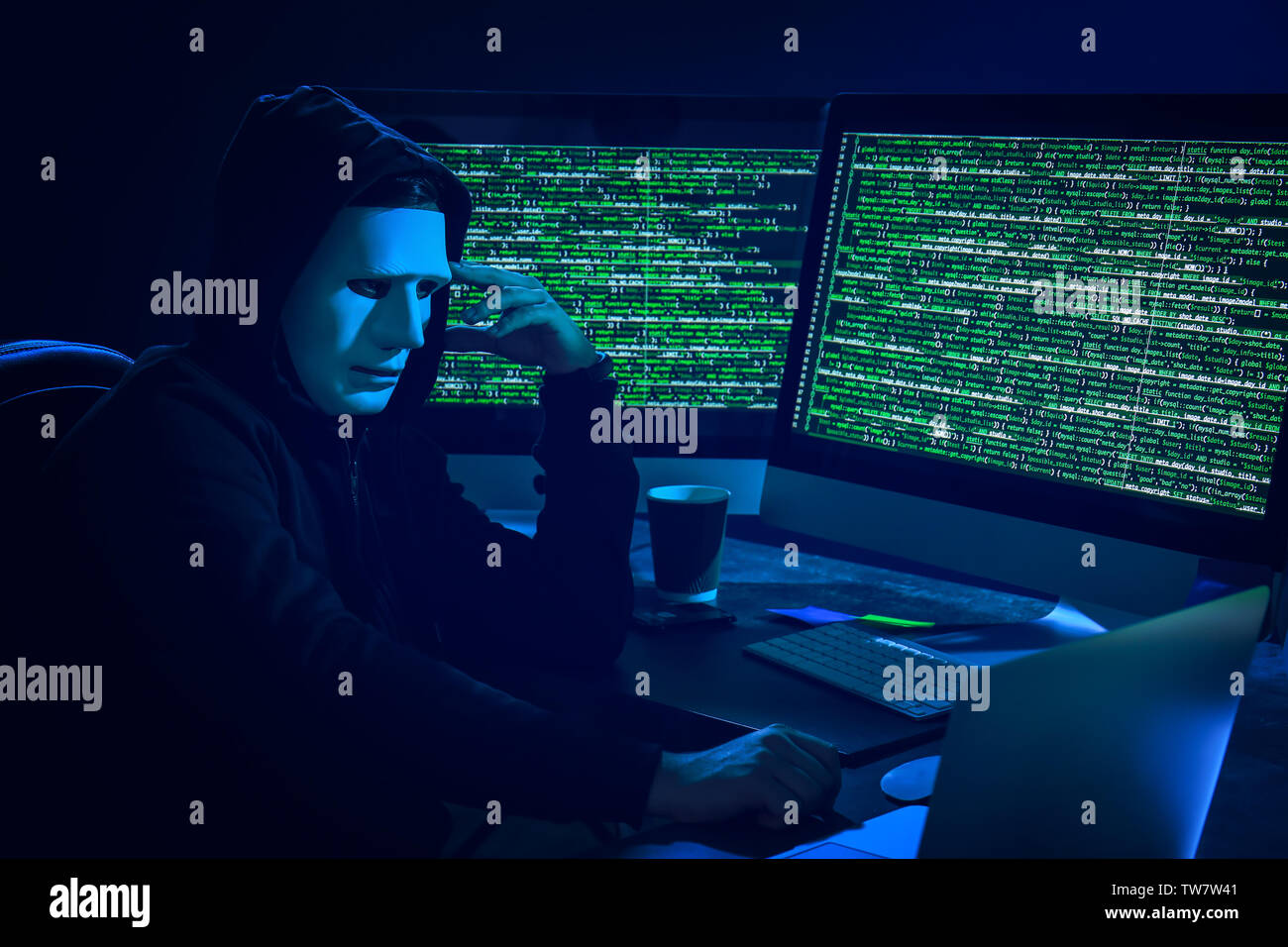 Hacker in mask using computer in dark room Stock Photo - Alamy