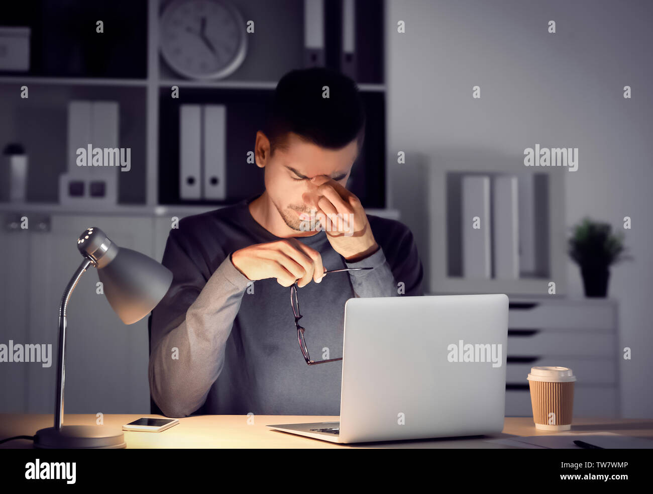 Tired man with laptop in office Stock Photo - Alamy