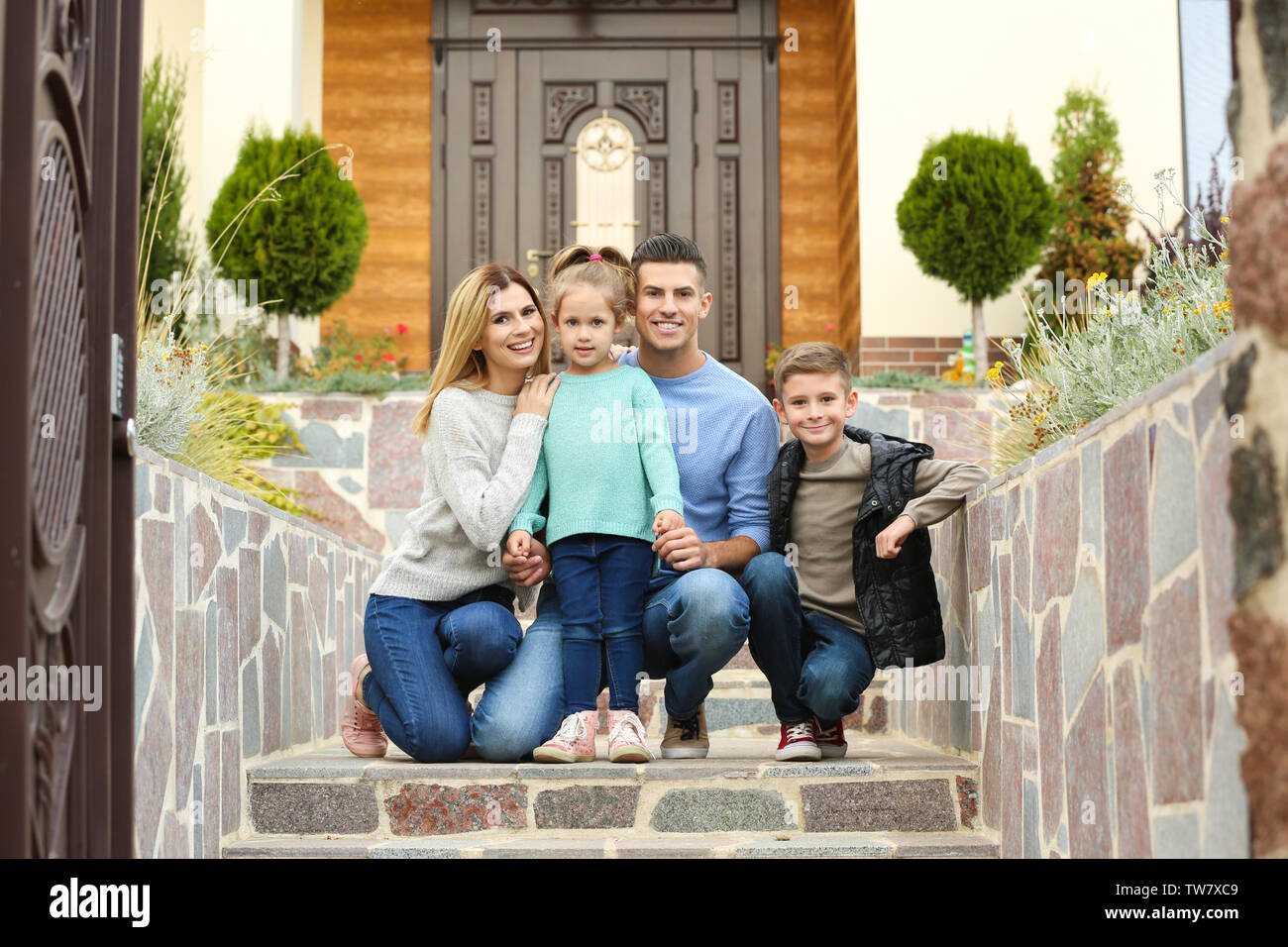 Happy family near their house entrance Stock Photo - Alamy