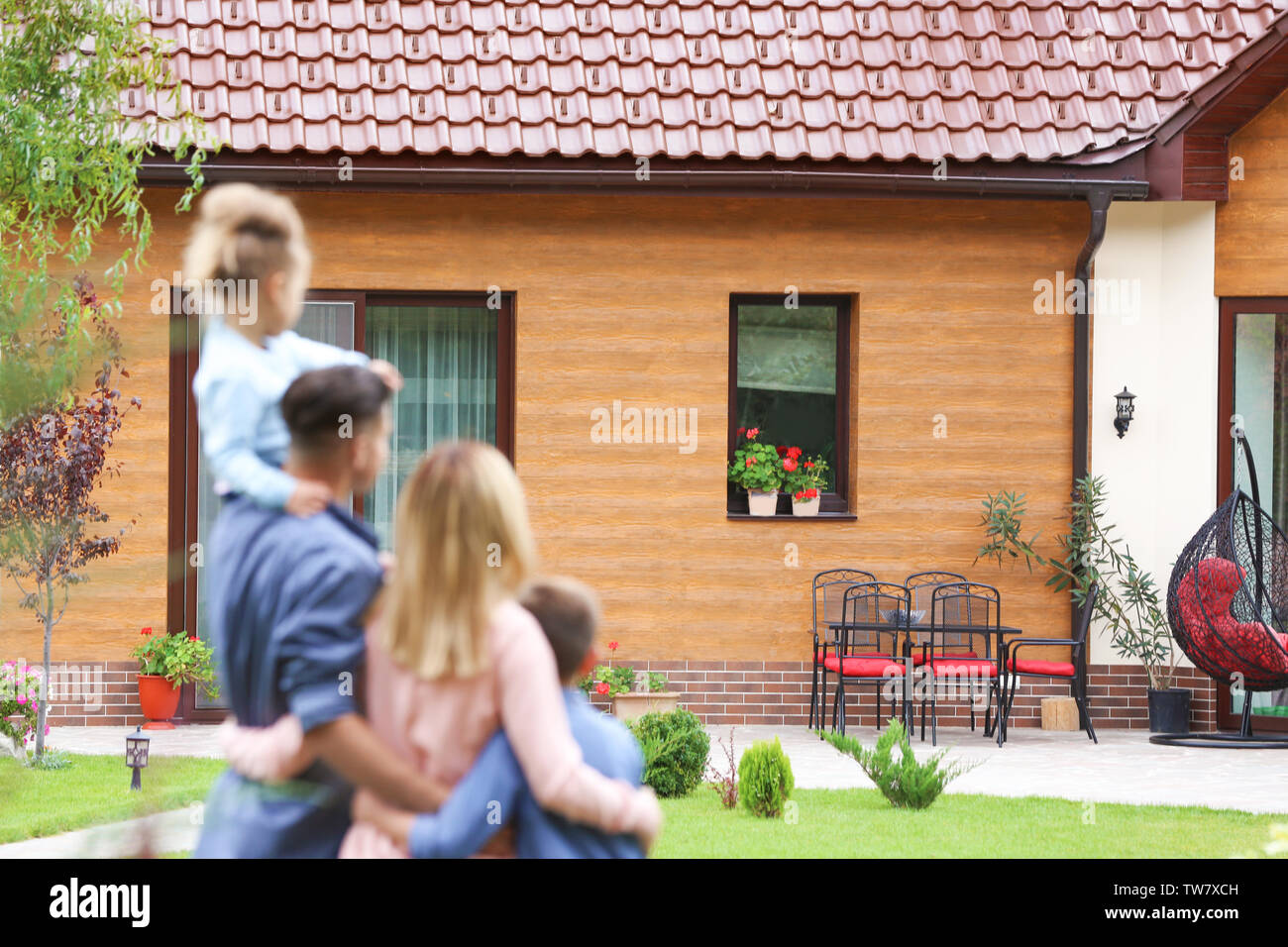 Happy family standing in courtyard and looking at their house Stock ...