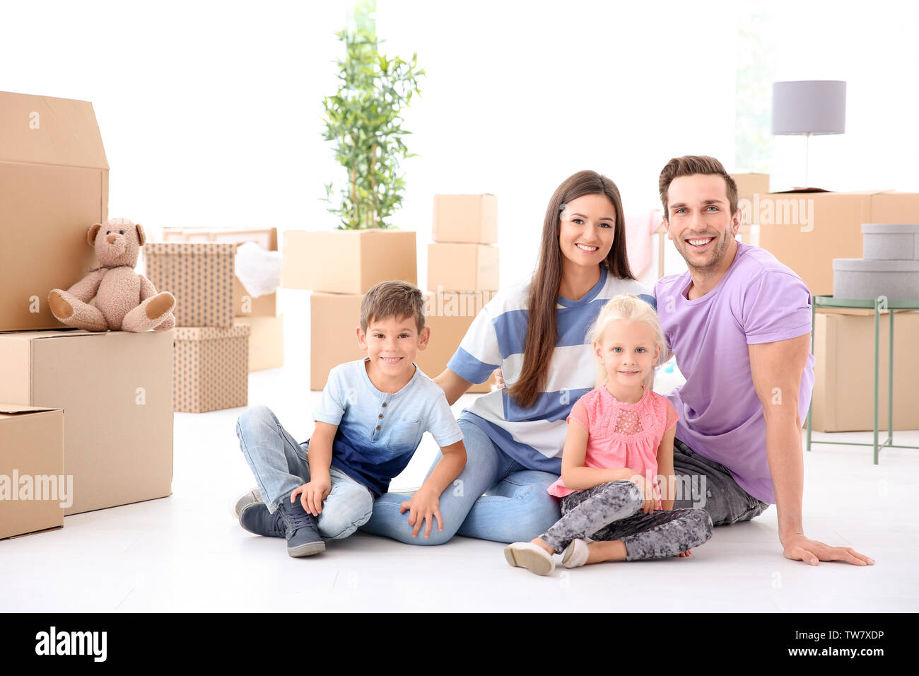 Happy family sitting on floor in their new home Stock Photo - Alamy