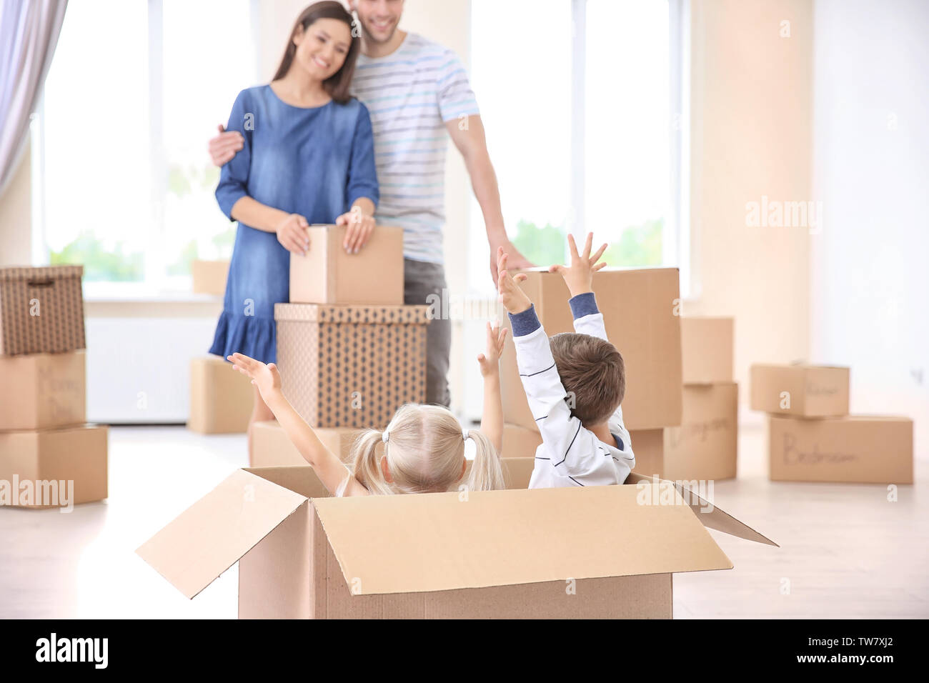 Happy siblings with parents having fun in their new home Stock Photo ...