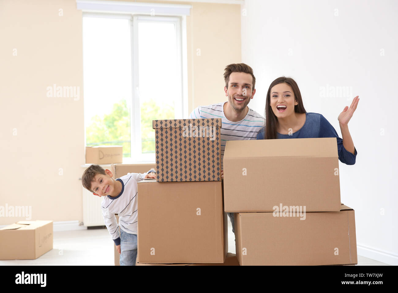 Happy family hiding behind boxes in their new home Stock Photo - Alamy