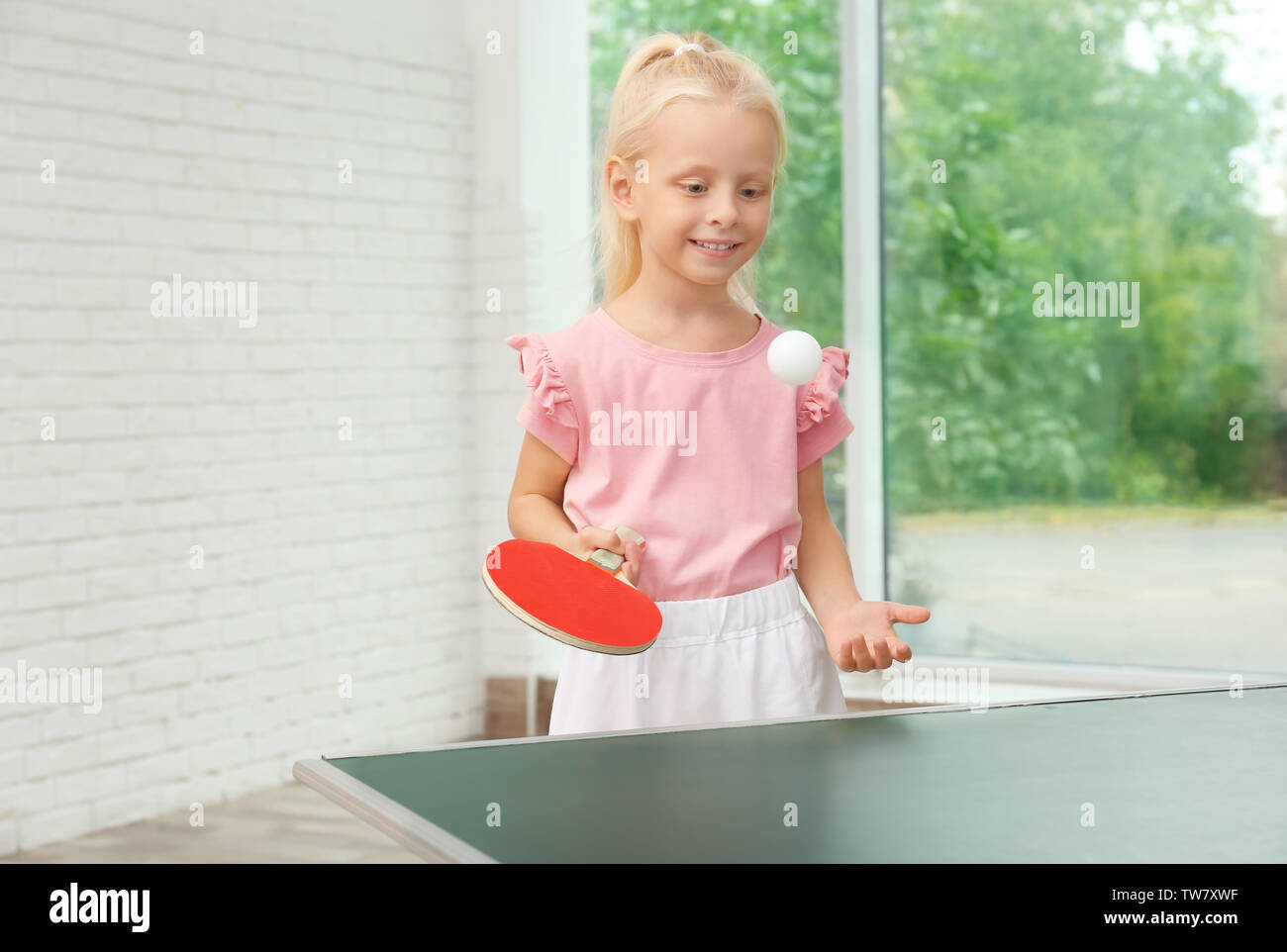 Cute little girl playing table tennis indoors Stock Photo - Alamy