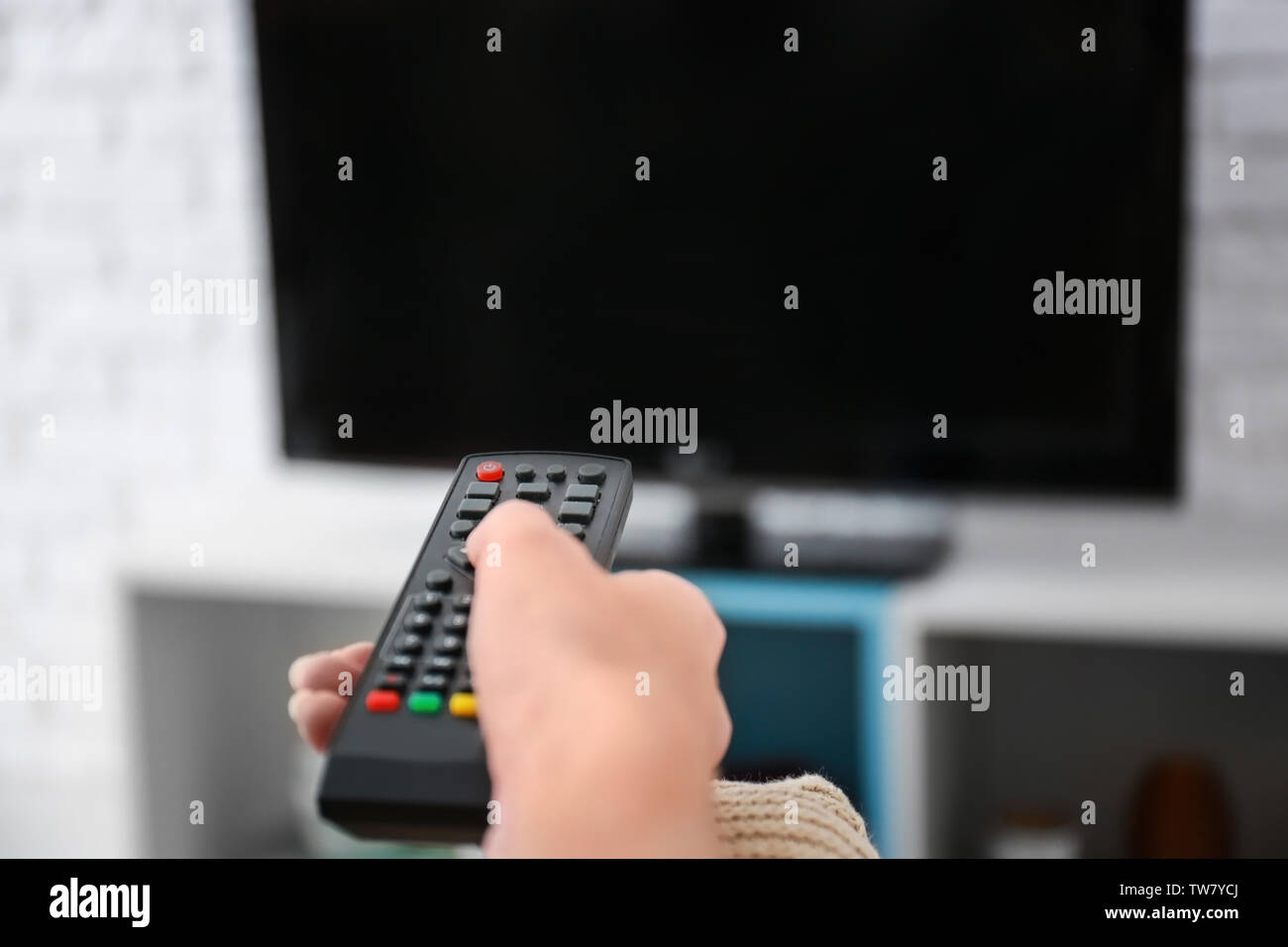 Woman with TV remote control switching channels, closeup Stock Photo ...