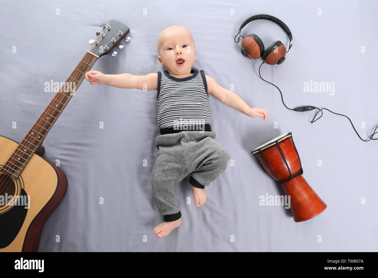 Cute baby with musical instruments and headphones on light background ...
