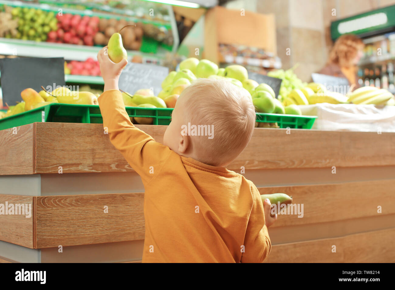 Cute little boy choosing pears in supermarket Stock Photo - Alamy