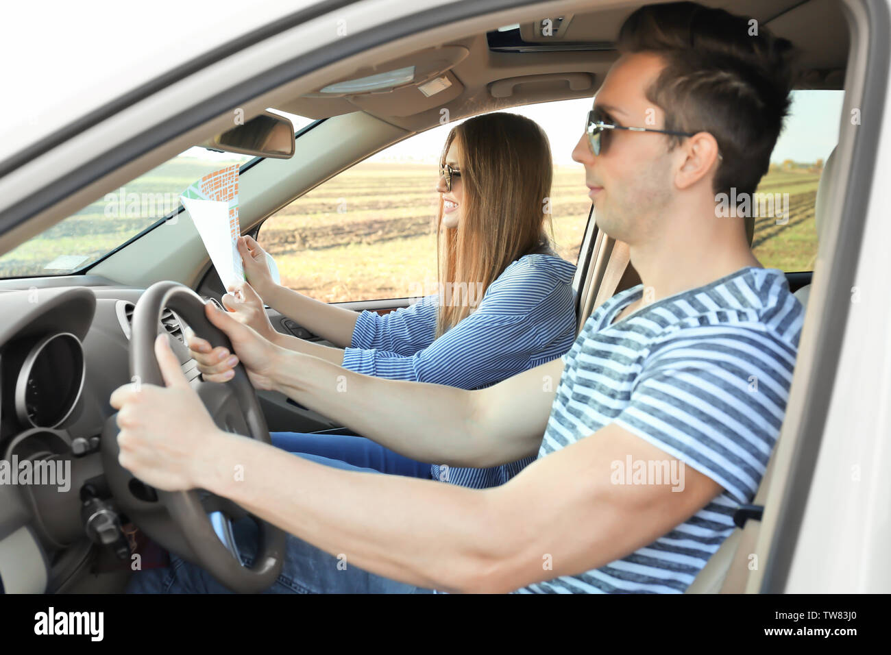 Beautiful young couple with map in car Stock Photo - Alamy
