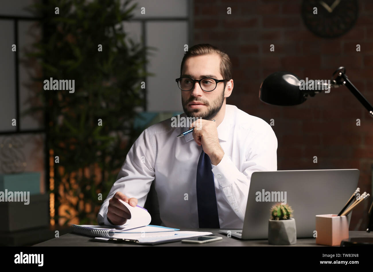 Tired young man working in office at night Stock Photo - Alamy