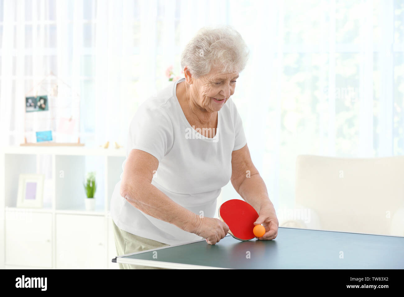 Senior woman playing table tennis indoors Stock Photo - Alamy