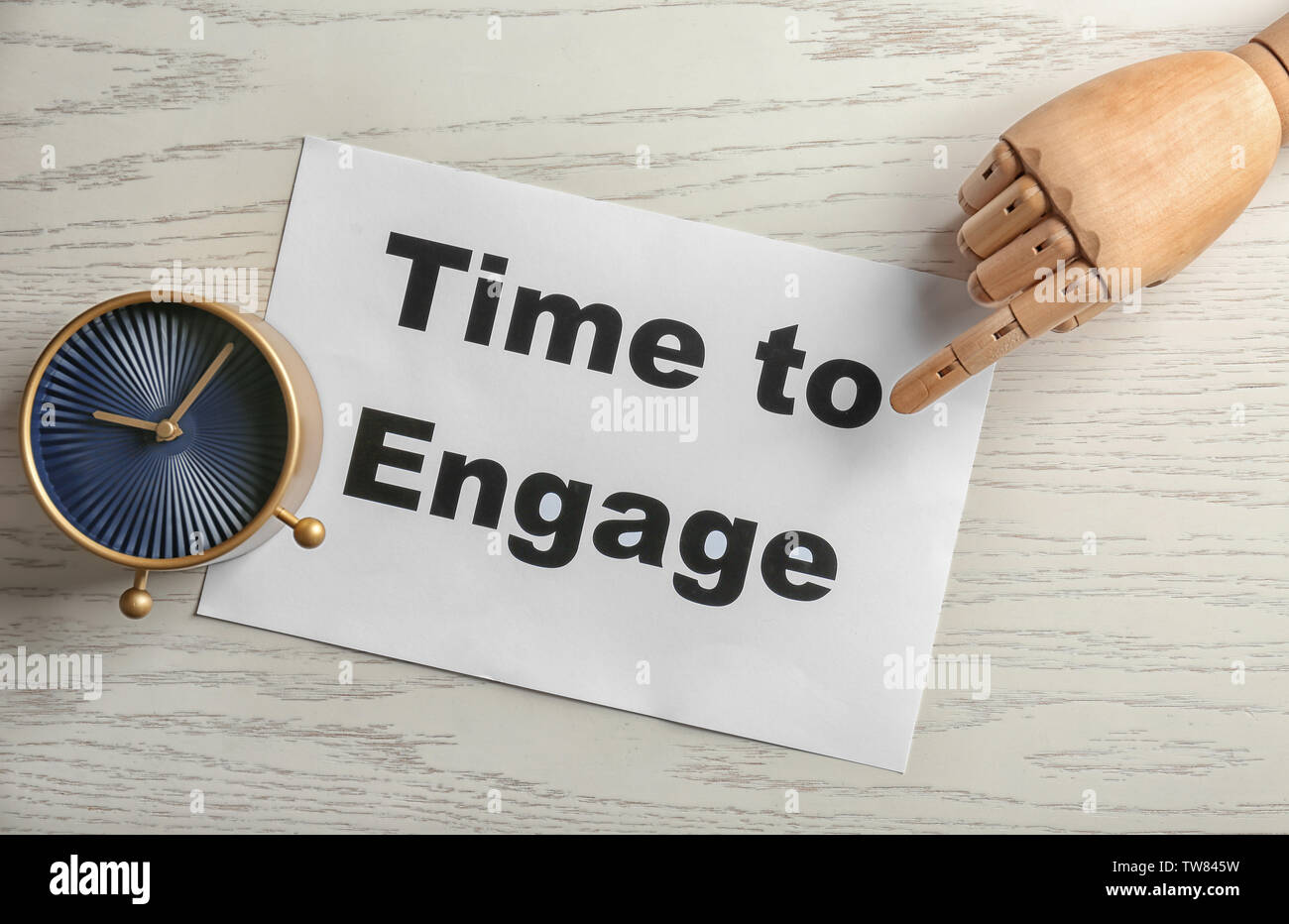 Clock and mannequin hand pointing at sheet of paper with phrase TIME TO ...