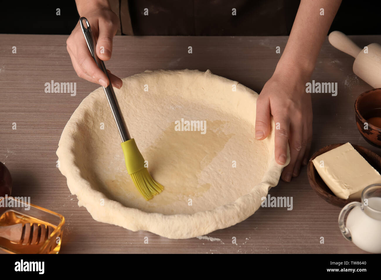 Woman spreading oil on puff pastry with brush Stock Photo - Alamy