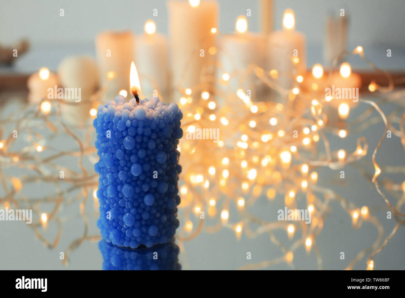 Burning color candle on blurred background Stock Photo - Alamy