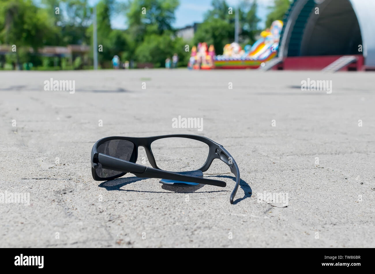 broken sunglasses lie on a stone-tiled walkway in the city Park against ...