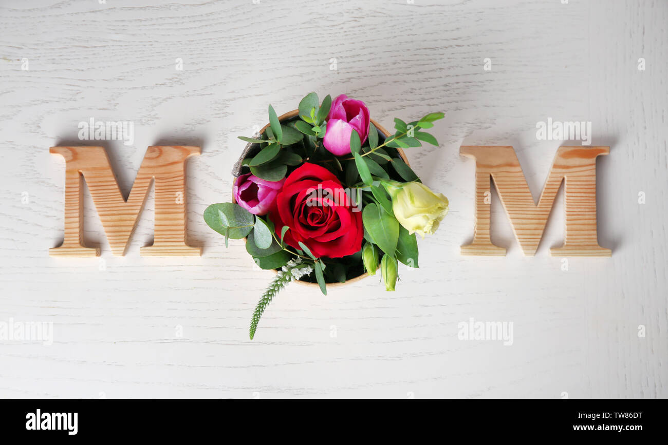 Word "Mom" and fresh flowers on light background. Mother's Day ...