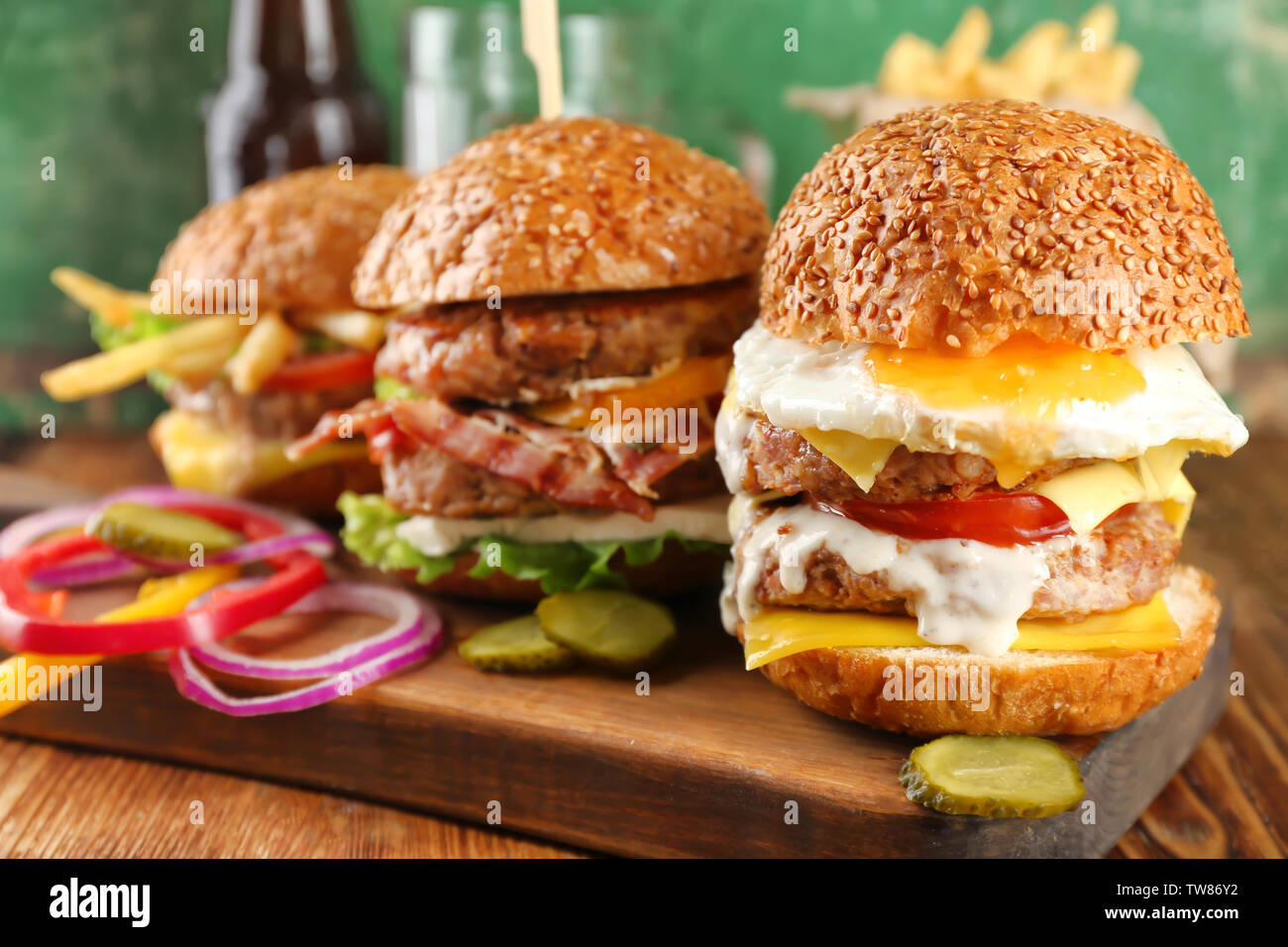 Board with tasty double burgers on table Stock Photo - Alamy