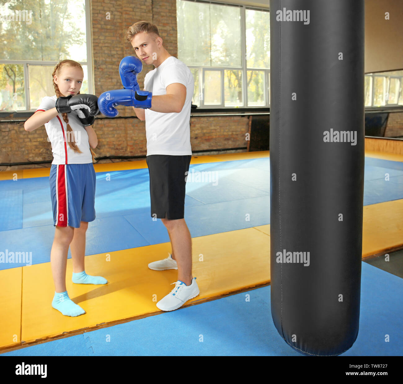 Little girl with trainer in boxing gloves indoors Stock Photo - Alamy