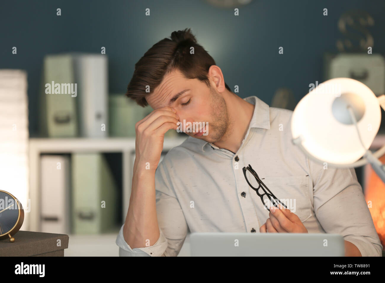 Tired young man working in office at night Stock Photo - Alamy