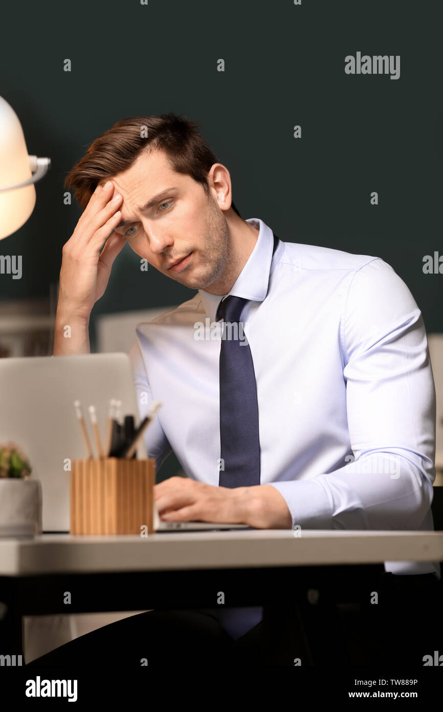 Tired young man working in office at night Stock Photo - Alamy