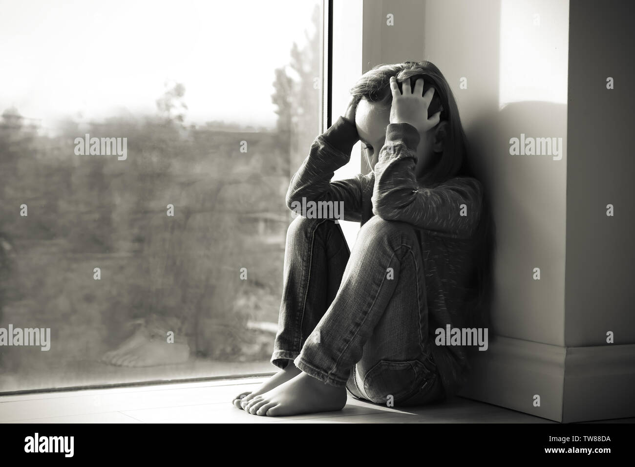 Little sad girl near window. Abuse of children concept Stock Photo - Alamy