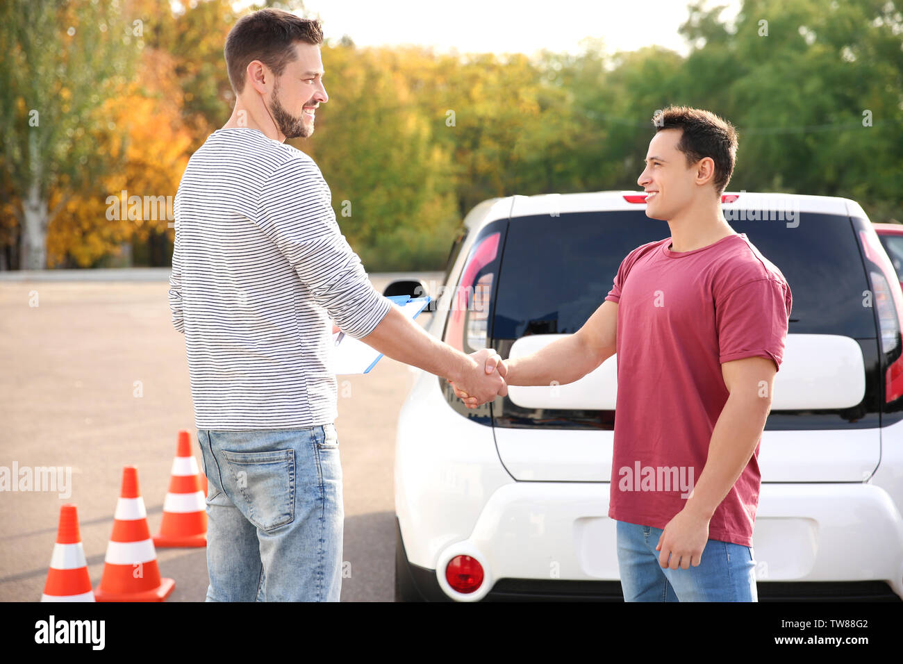 Instructor and young man passed driving license exam Stock Photo - Alamy