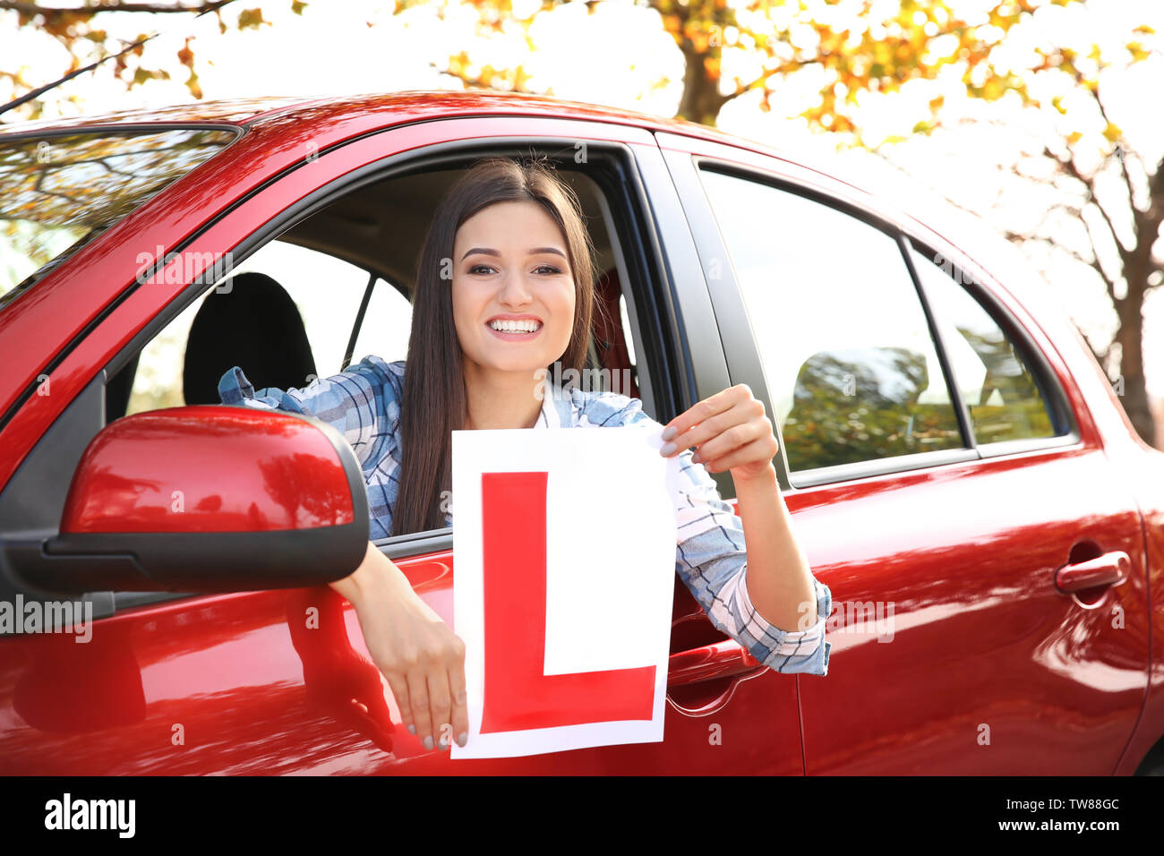 Happy young woman holding learner driver sign in car Stock Photo - Alamy
