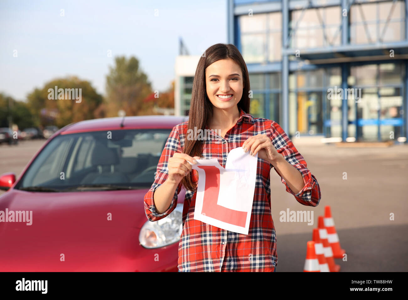 Happy young woman tearing learner driver sign near car Stock Photo - Alamy