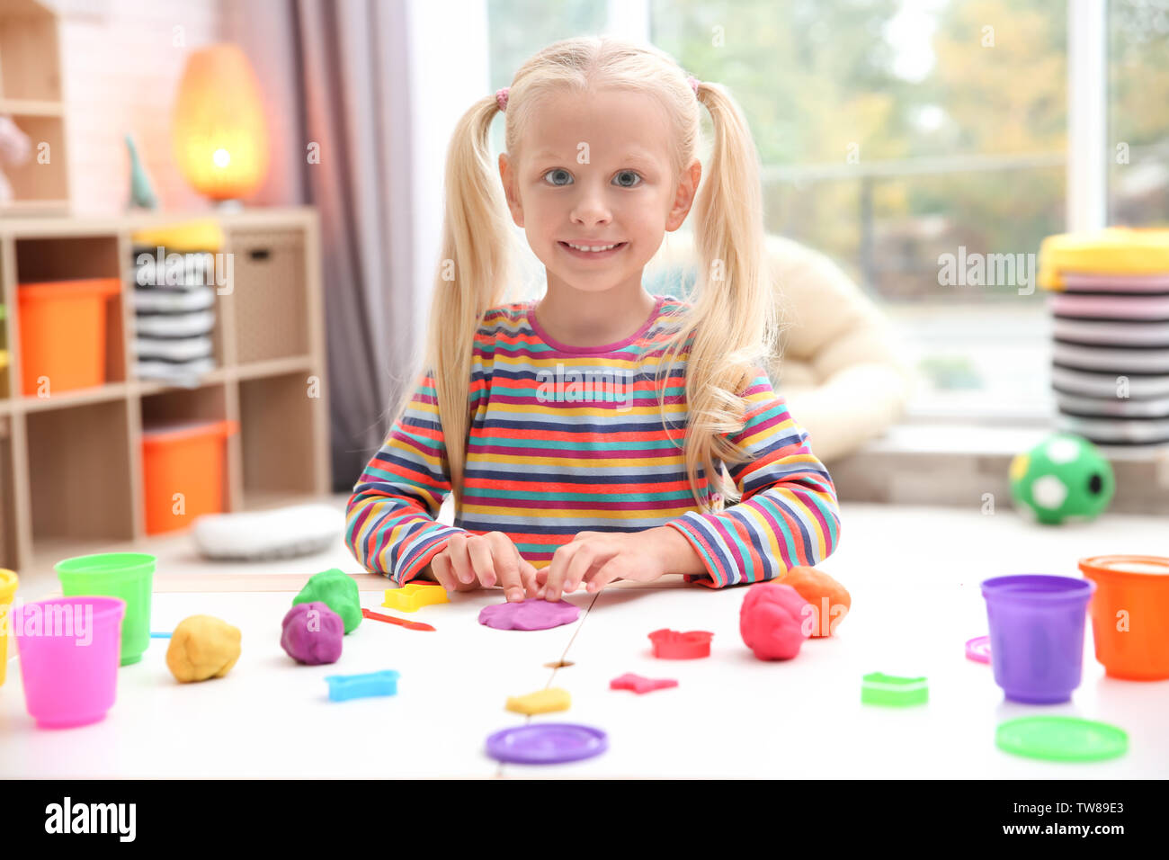 Little girl engaged in playdough modeling at daycare Stock Photo - Alamy