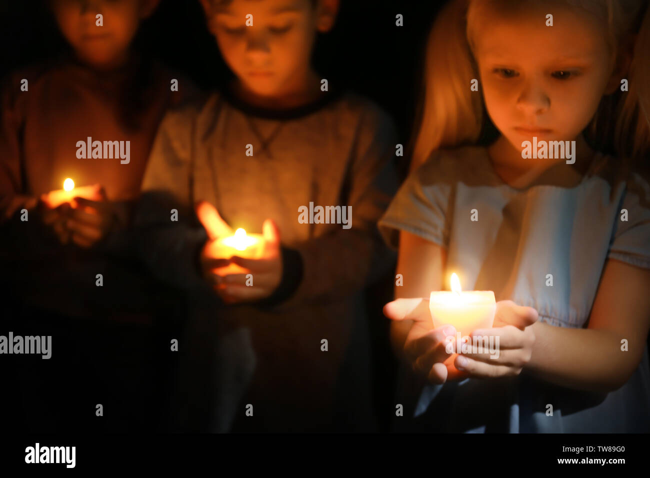 Little children holding burning candles in darkness Stock Photo - Alamy