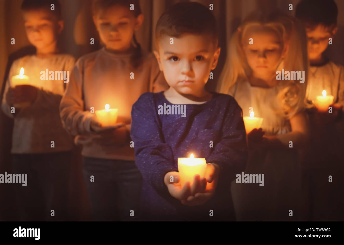 Little children holding burning candles in darkness Stock Photo - Alamy