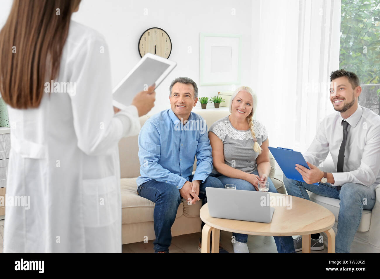Female doctor with clients at insurance agency Stock Photo - Alamy