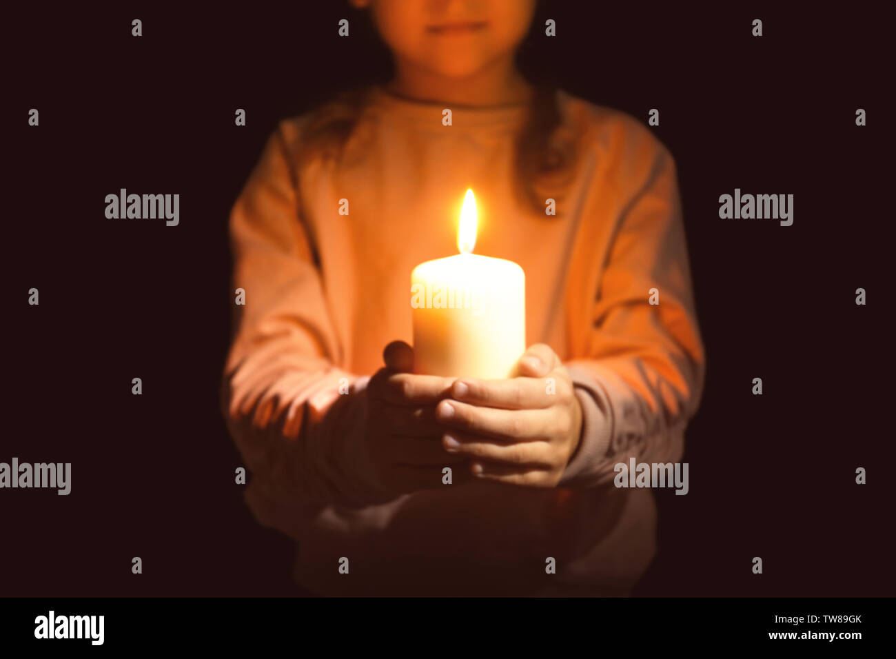 Little girl holding burning candle in darkness Stock Photo - Alamy