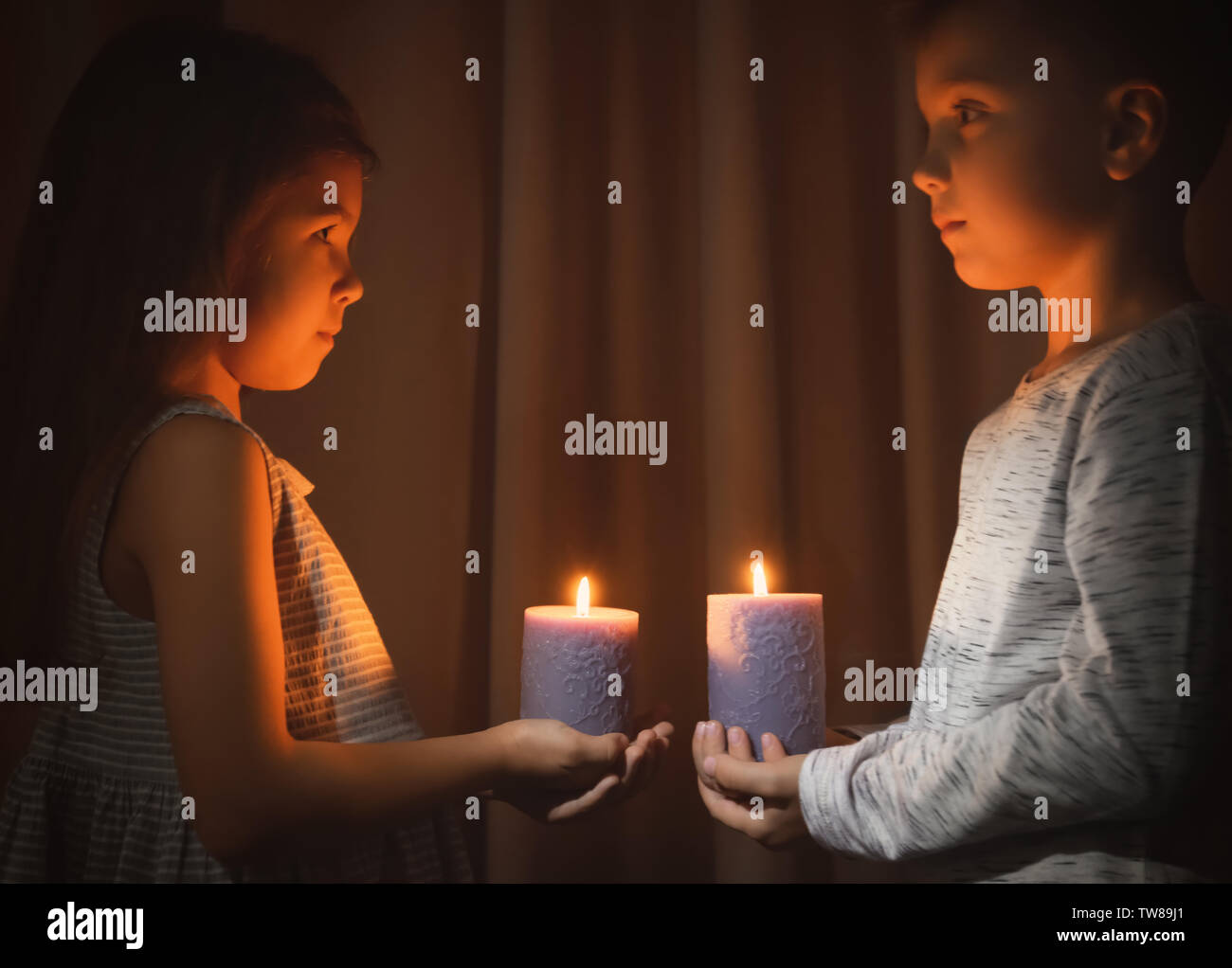Little children holding burning candles in darkness Stock Photo - Alamy