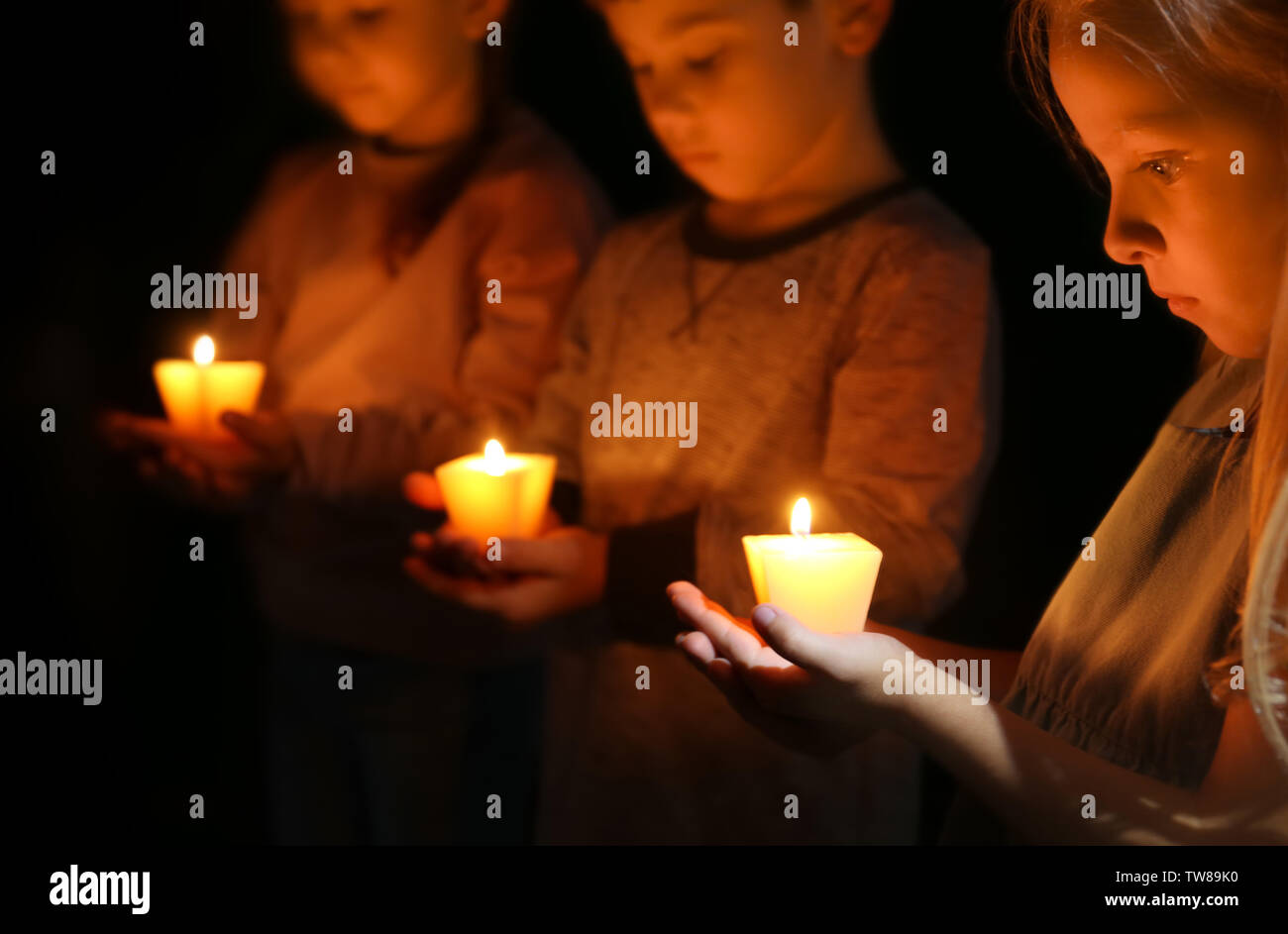 Little children holding burning candles in darkness Stock Photo - Alamy