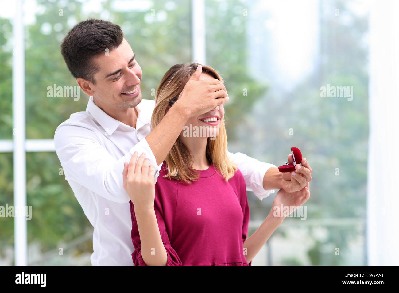 Man with engagement ring making proposal of marriage to woman at home ...
