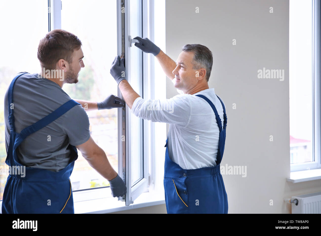 Construction worker with trainee installing window in house Stock Photo ...