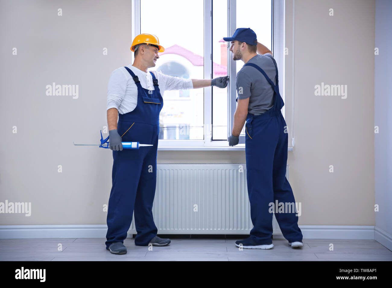 Construction worker with trainee installing window in house Stock Photo ...