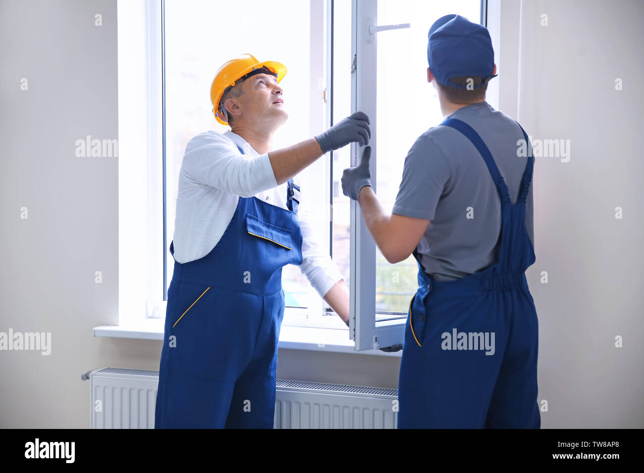 Construction worker with trainee installing window in house Stock Photo ...