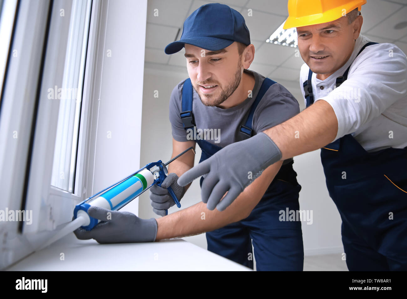 Construction worker with trainee installing window in house Stock Photo ...