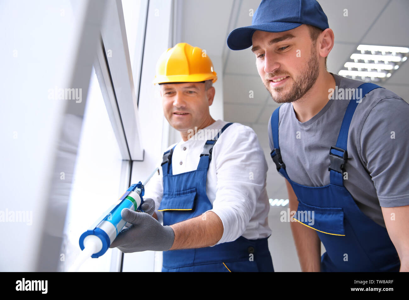 Construction worker with trainee installing window in house Stock Photo ...
