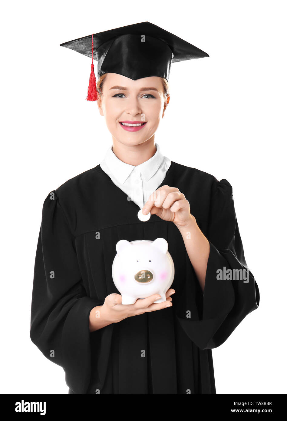 Young graduate putting coin into piggy bank on white background Stock ...