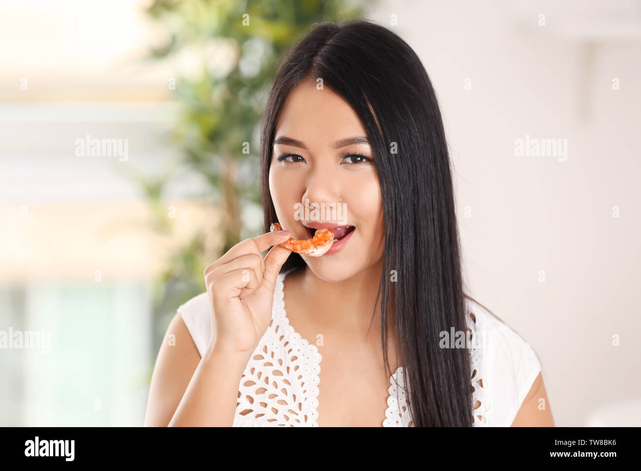 Beautiful Asian woman eating shrimp, indoors Stock Photo - Alamy