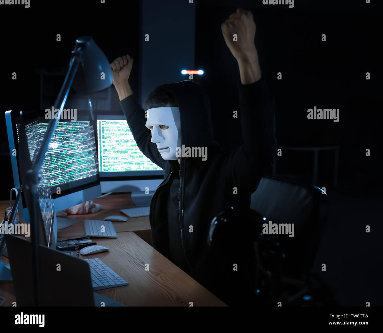 Masked hacker using computer in dark room. Threat of cyber attack Stock ...