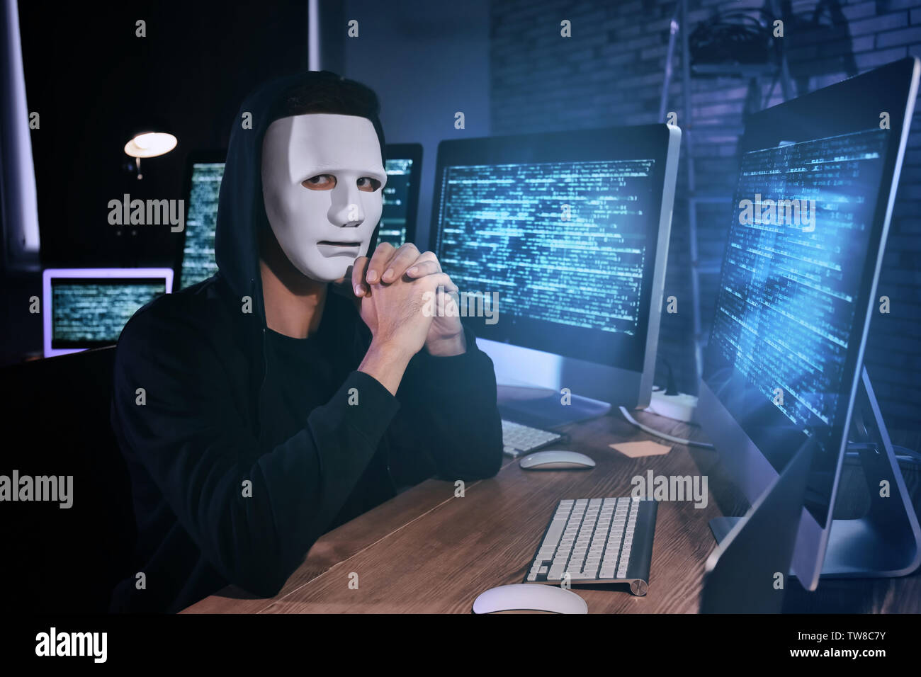 Masked hacker in dark room with computers. Threat of cyber attack Stock ...