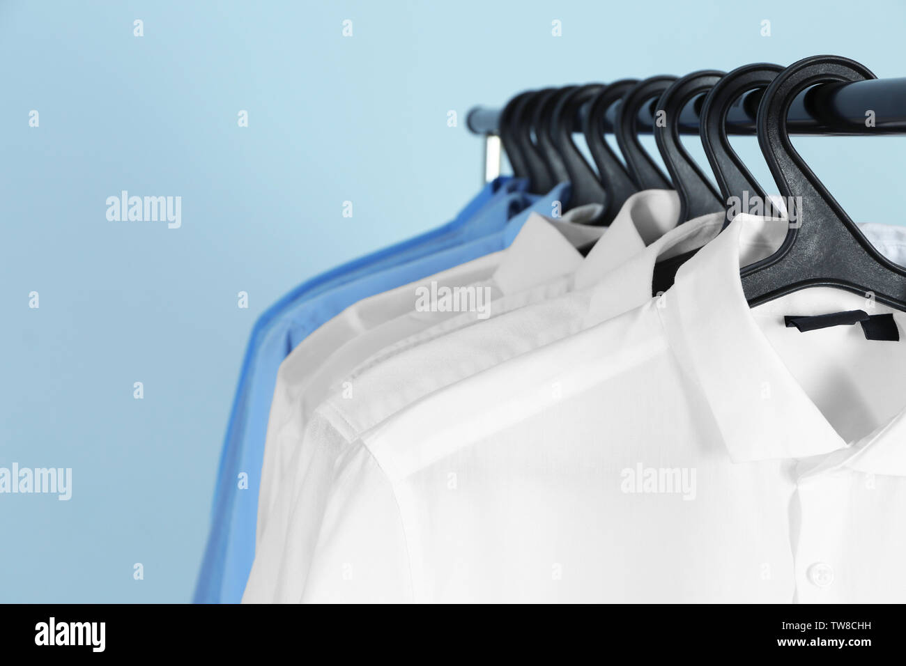 Clean shirts hanging on rack in laundry Stock Photo - Alamy