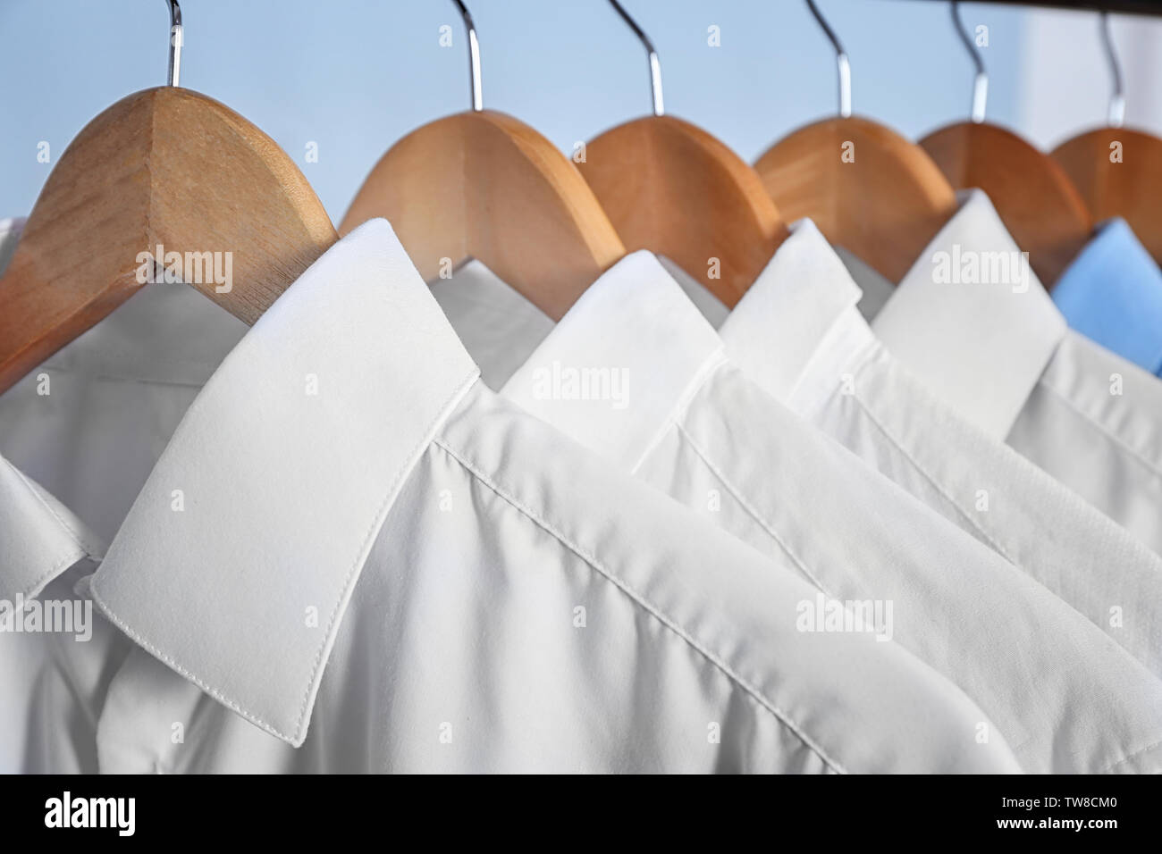 Clean shirts hanging on rack in laundry, closeup Stock Photo - Alamy